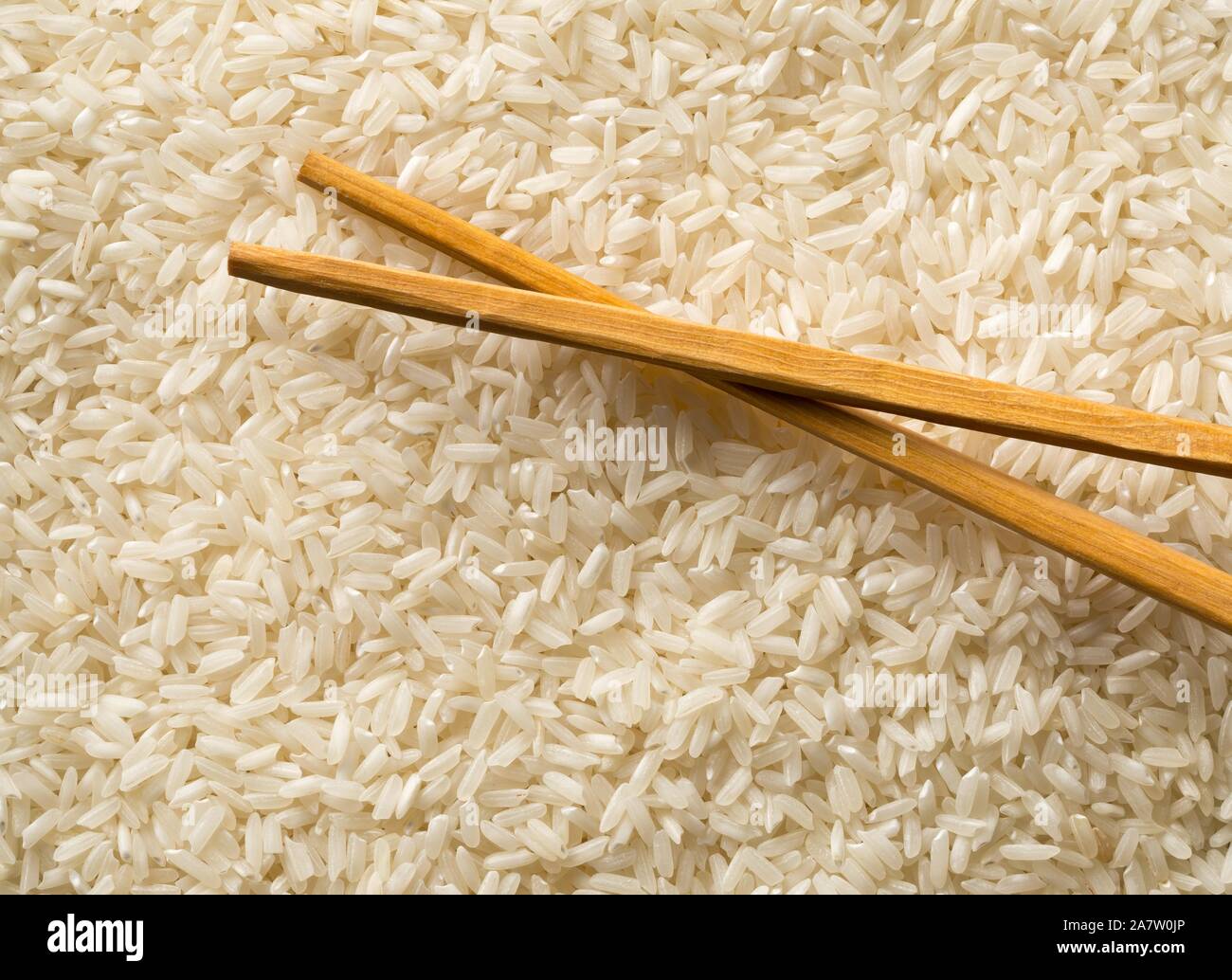 White uncooked, raw long grain rice full frame with chopsticks top view ...