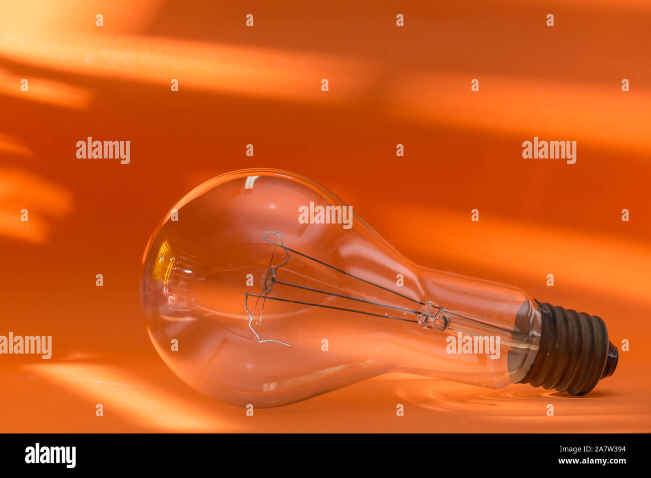 large bulb that has a broken filament, is placed on an orange ...