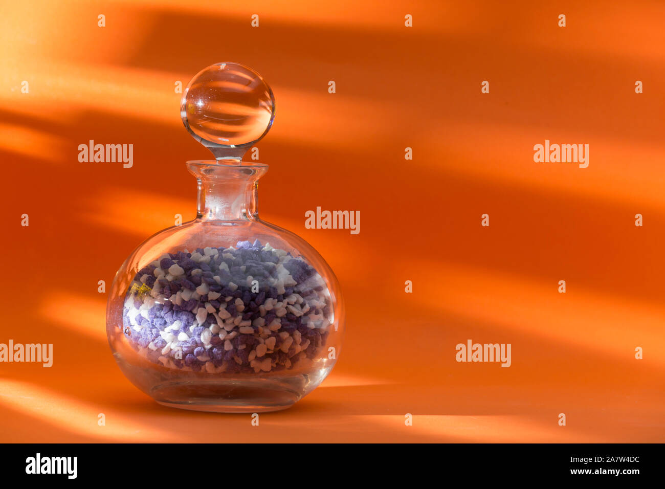 glass jar with ball cap, full of colored pebbles, centered on an orange ...