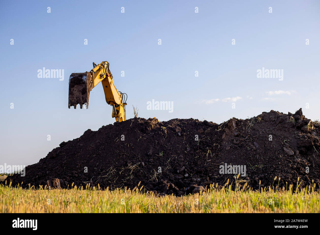 excavator digging dirt in the field Stock Photo - Alamy