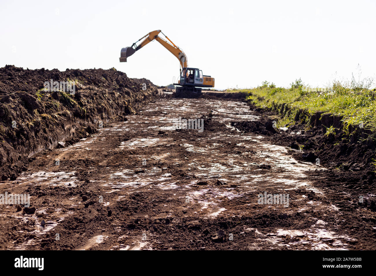 Excavator digging dirt in the field Stock Photo - Alamy