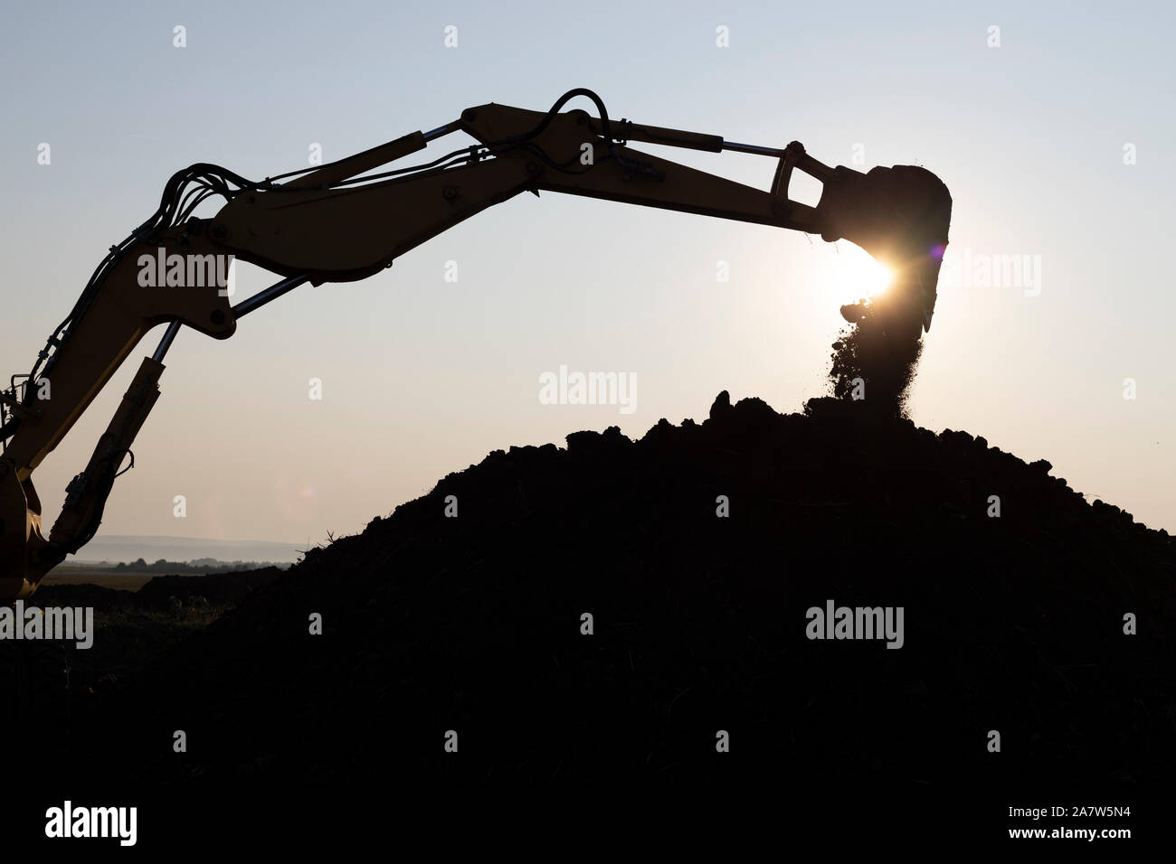 Silhouette of excavator digging dirt Stock Photo - Alamy