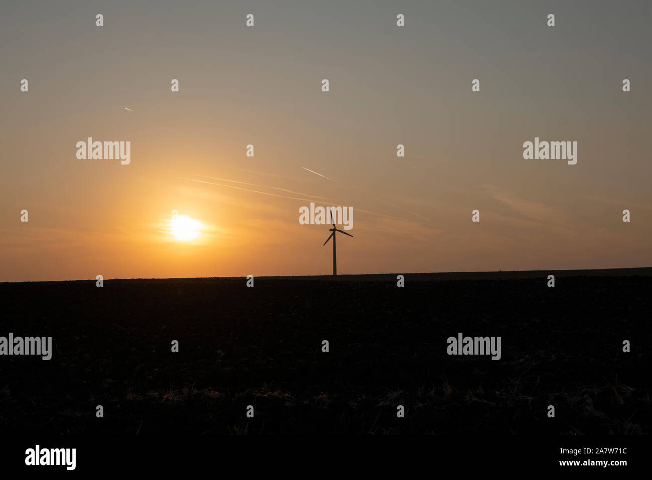 Wind turbine against sunset background Stock Photo - Alamy