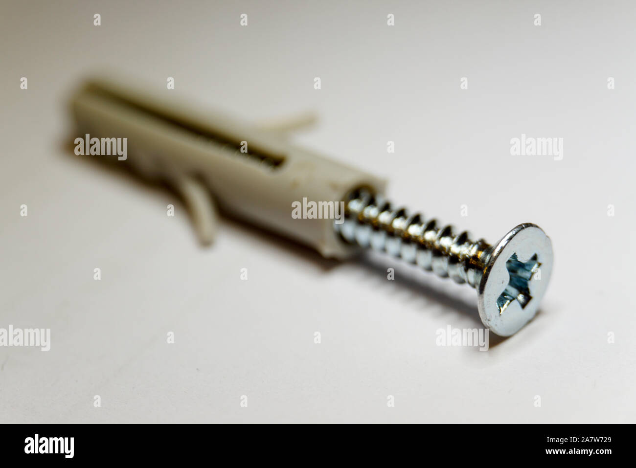 Macro close-up of chrome screw thread and beige dowel on white ...