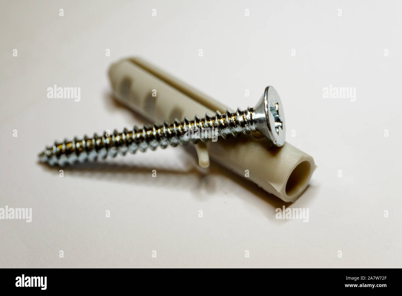 Macro close-up of chrome screw thread and beige dowel on white ...