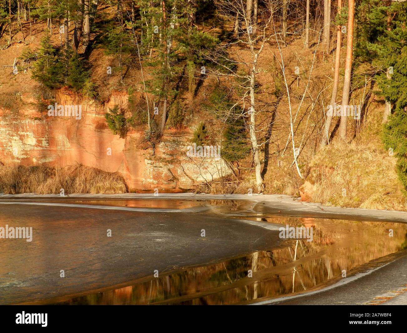 sandstone cliff in sunset light, reflections in water Stock Photo - Alamy