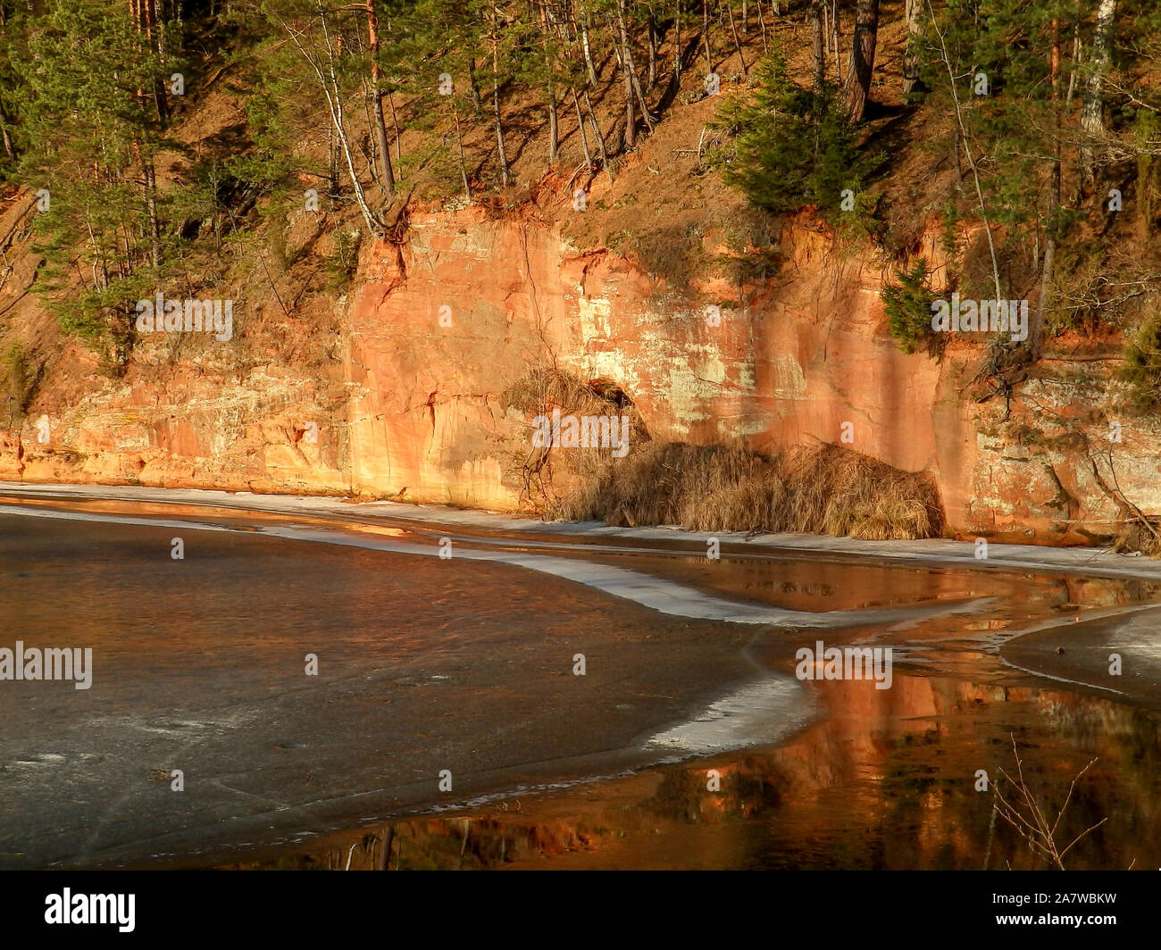 sandstone cliff in sunset light, reflections in water Stock Photo - Alamy