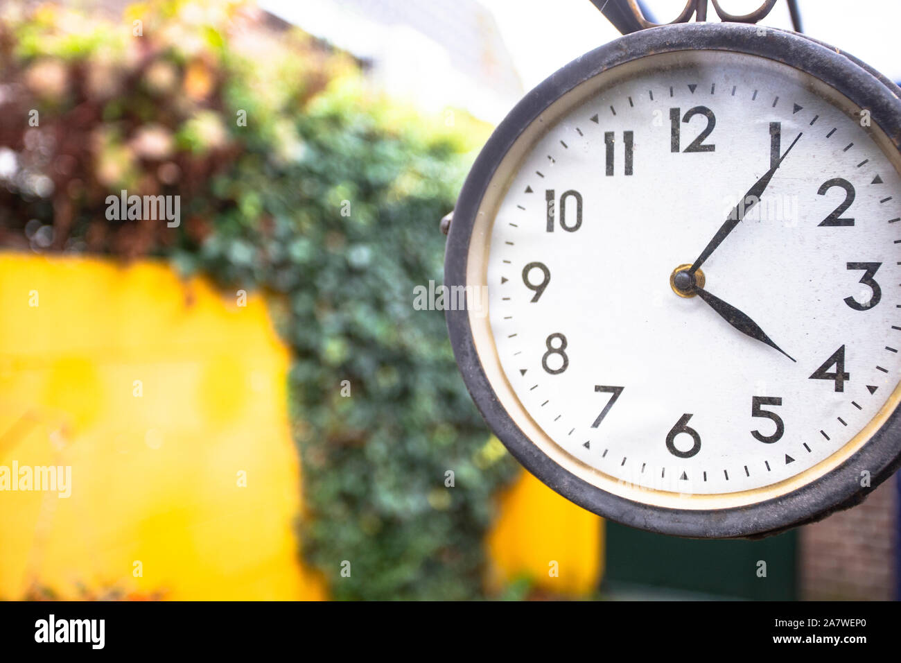 Antique vintage style clock hanging outside, hanging on the wall of a ...