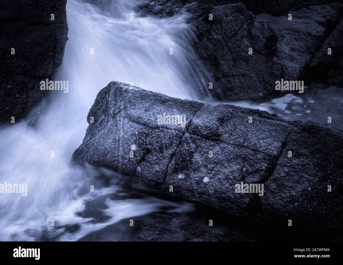Wave splashing on dark and wet rocks.Coastal landscape scene with ...