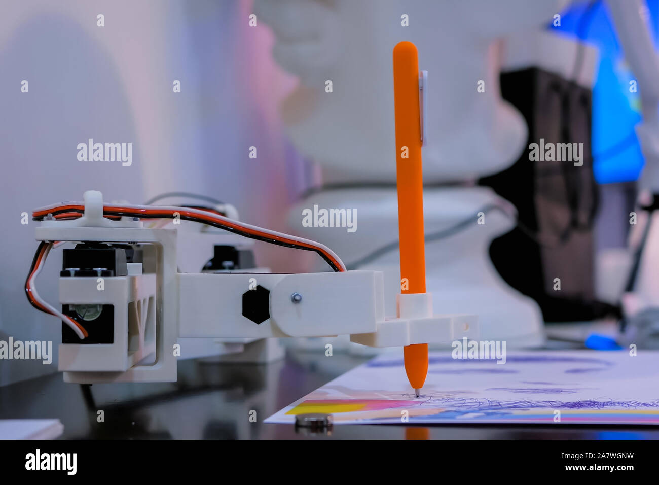 Robotic arm with orange pen drawing portrait at robot futuristic ...