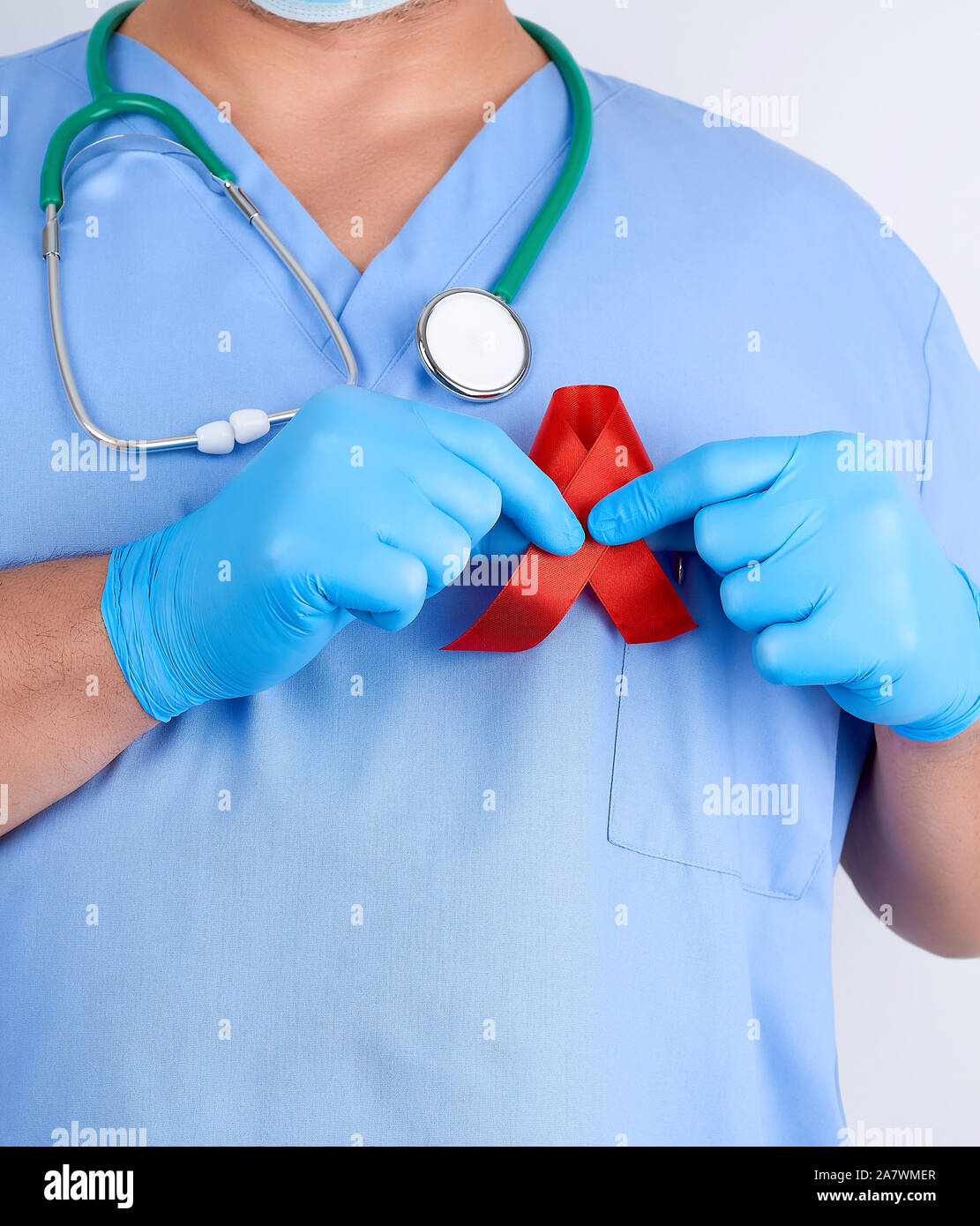 doctor in blue uniform and sterile latex gloves holds a red ribbon ...