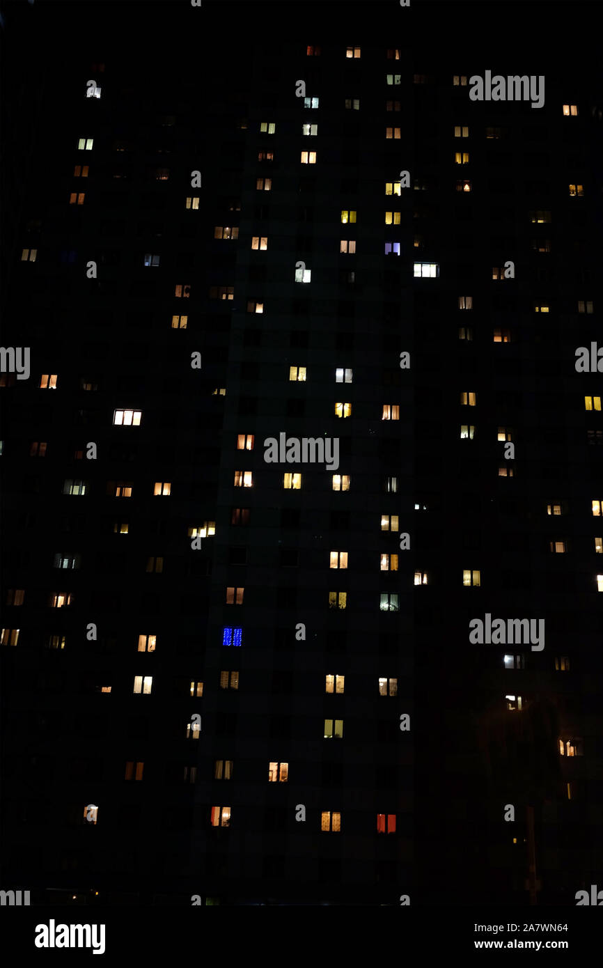Facade of large multi-storey block of flats with many bright lighting ...
