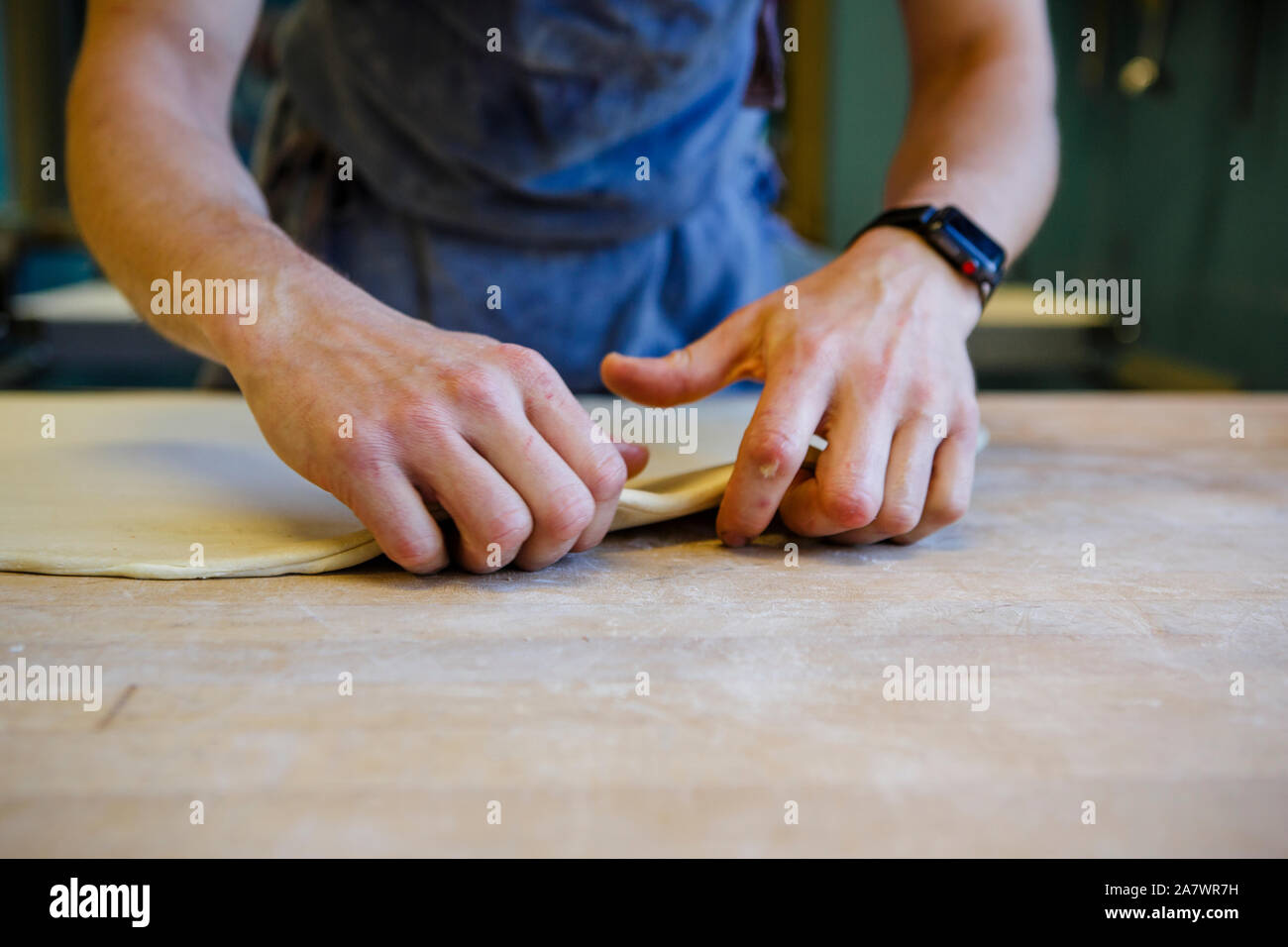 A baker working in a commercial kitchen folding pastry dough Stock ...