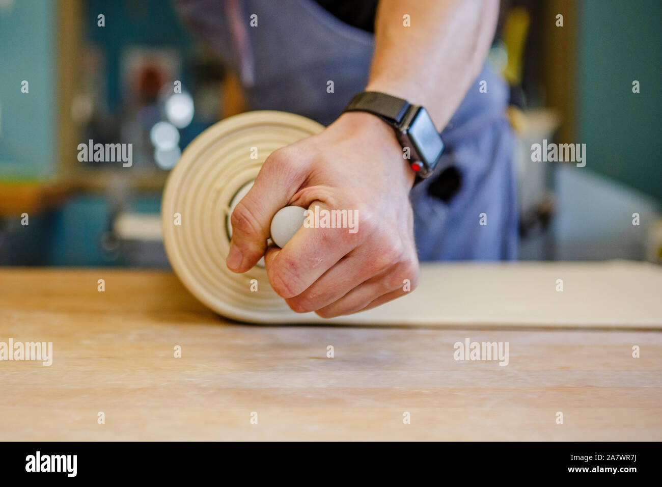 Close-up view of long sheet of dough being rolled out on wood counter ...