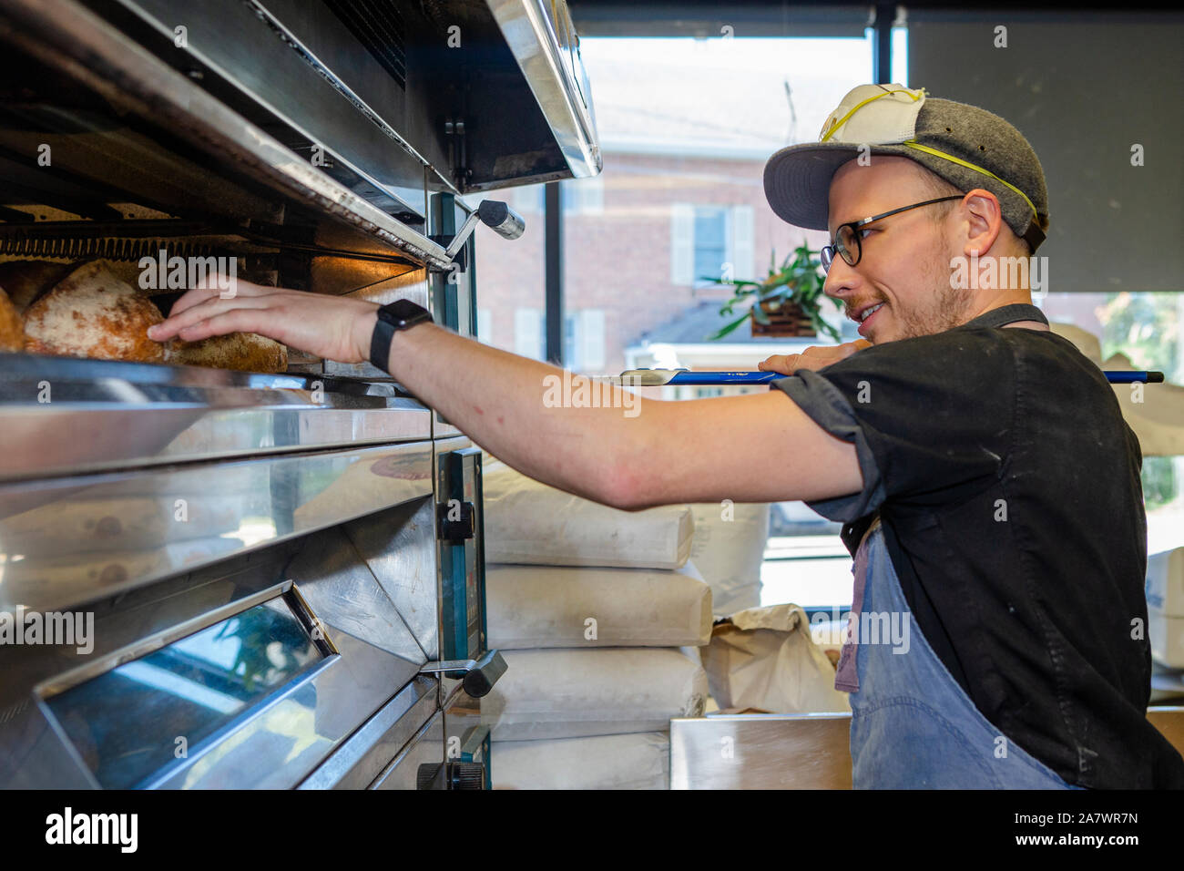 A smiling baker test loaves of bread in commercial kitchen Stock Photo ...