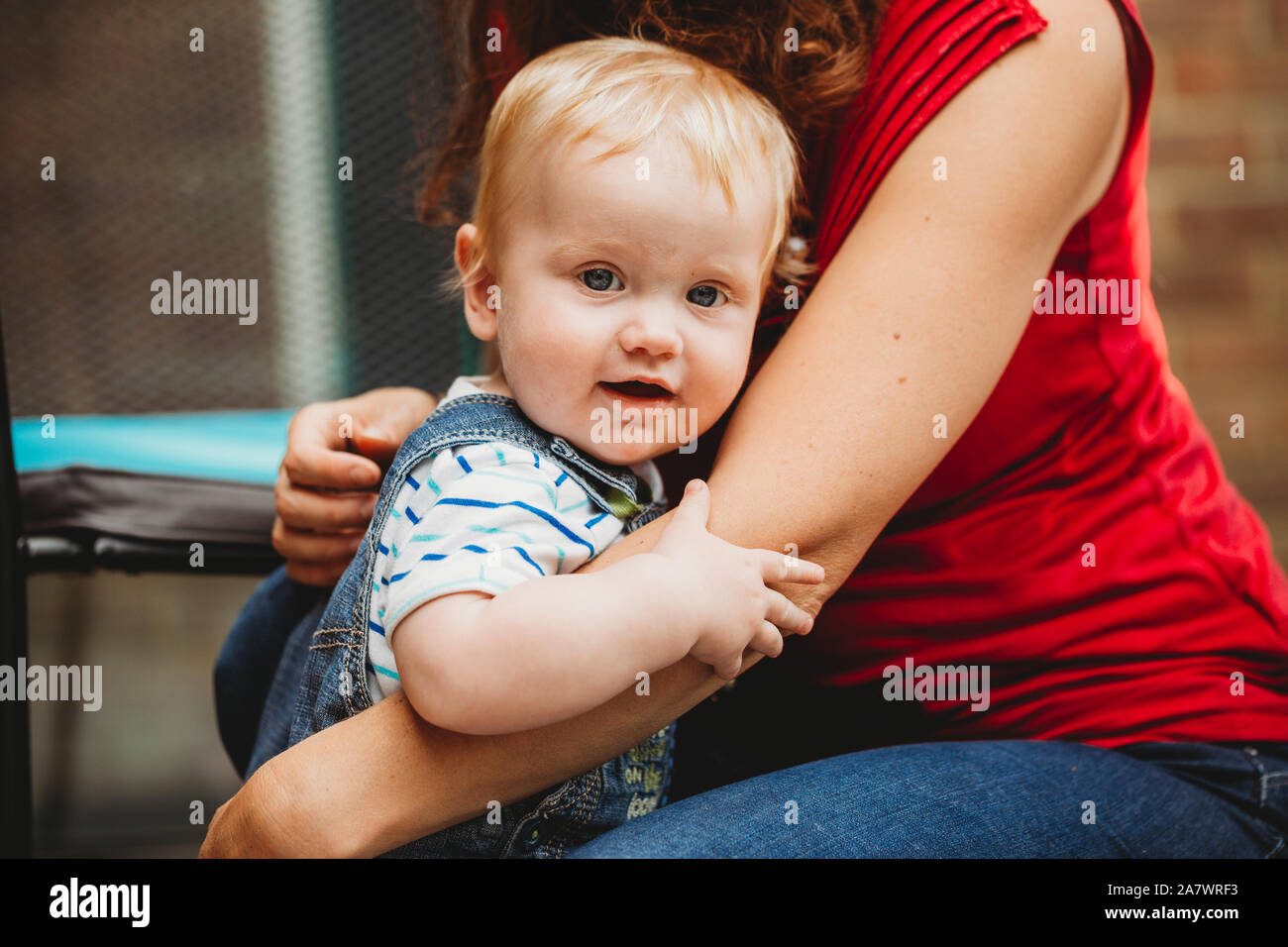 Cute baby boy holding onto mother's arm Stock Photo - Alamy