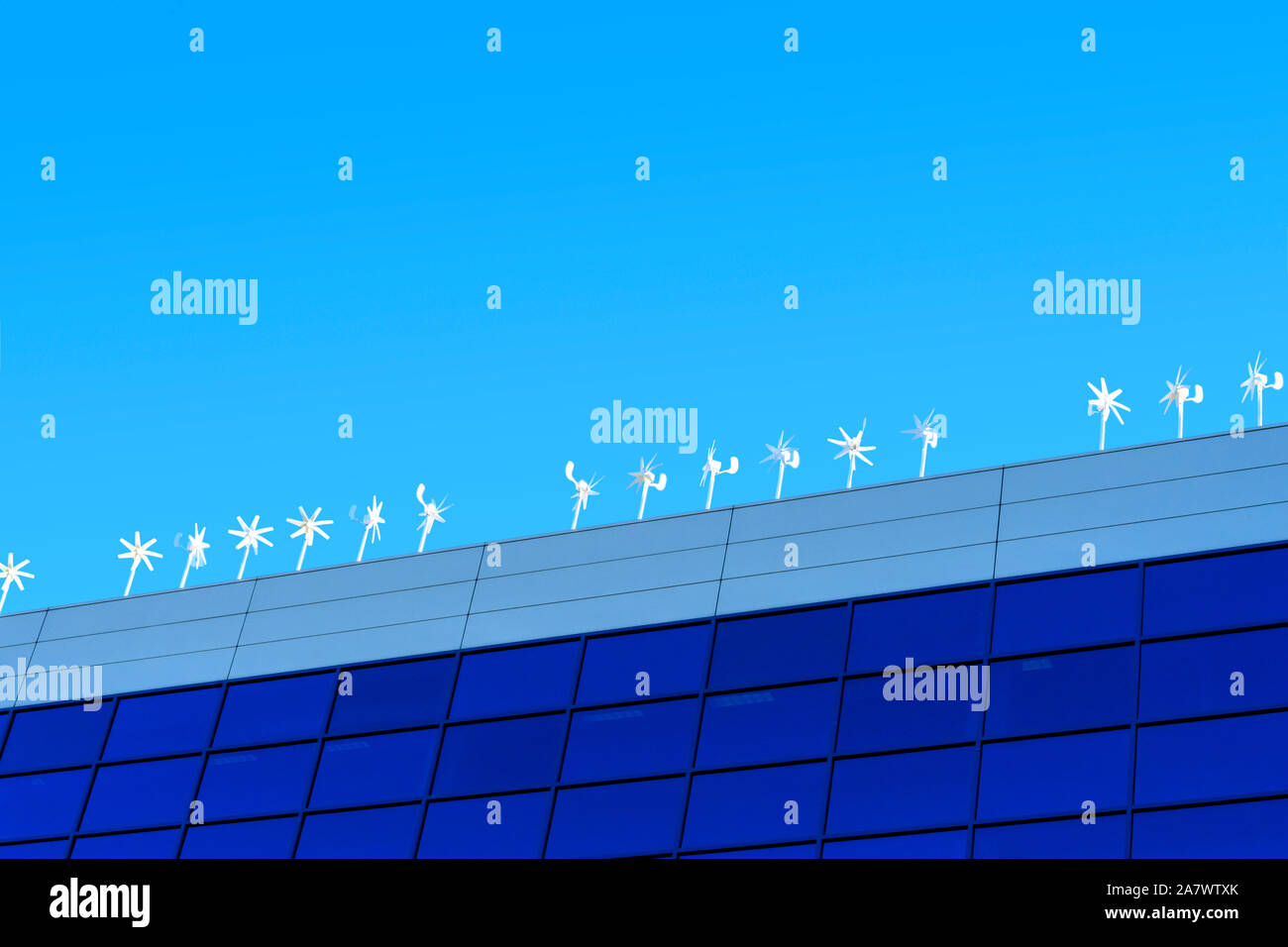 Wind turbines producing energy on top of modern office building on a ...