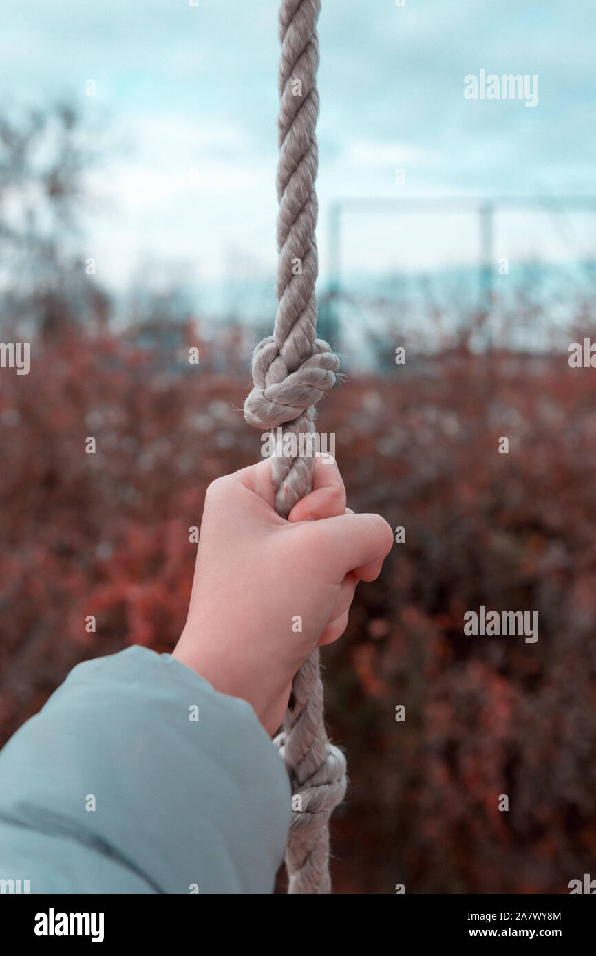 Woman hand holding the rope. Girl hand clinging to the rope, closeup ...
