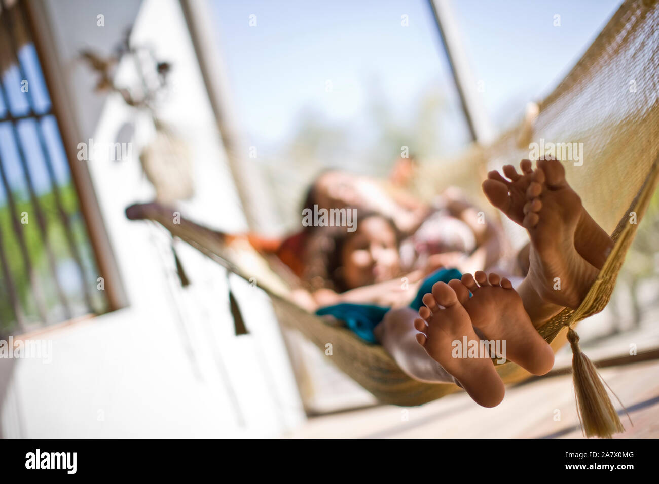 Feet of a mid-adult woman and her daughter lying in a hammock Stock ...