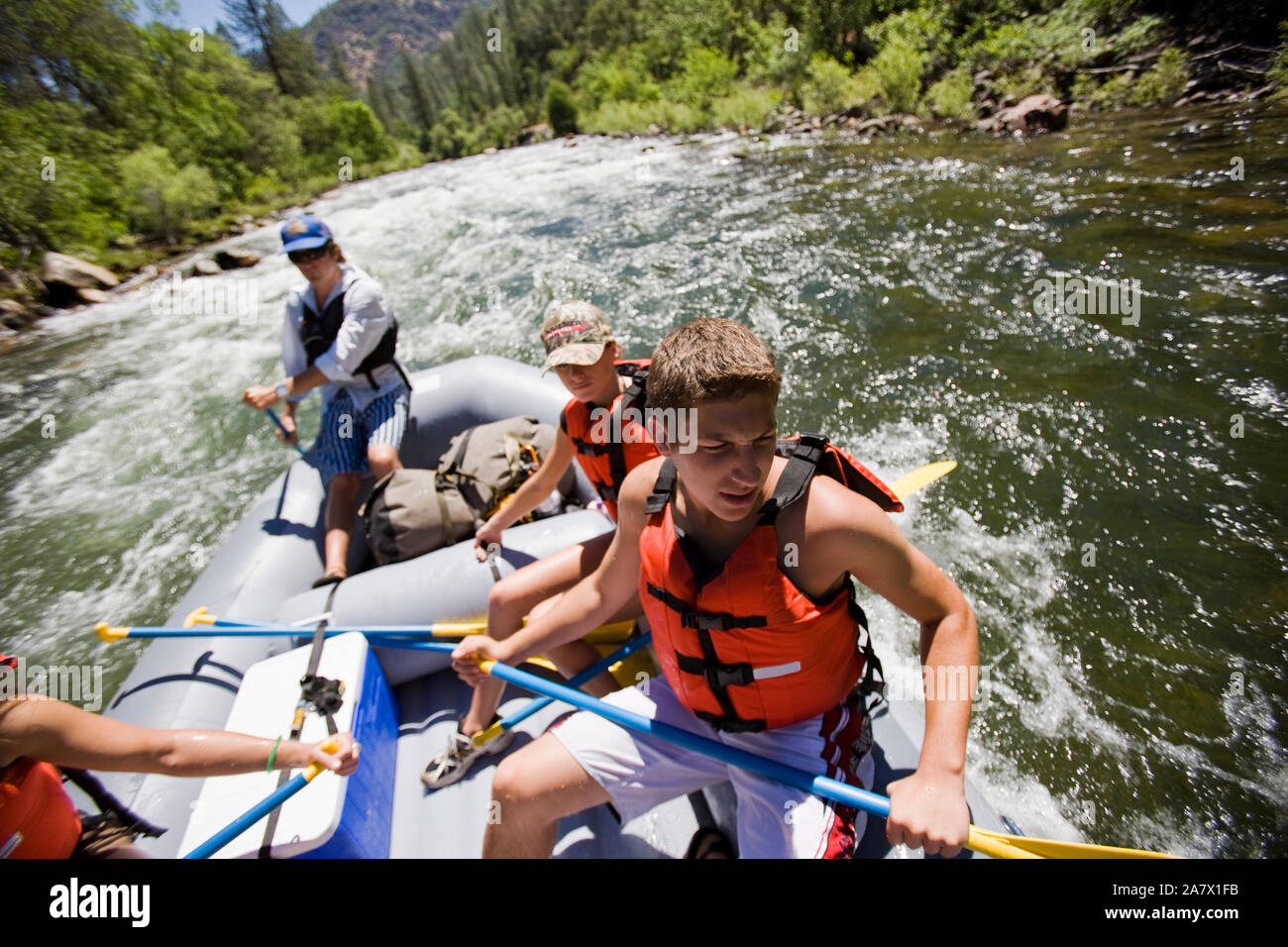 Teenage boy and friends rafting along a river Stock Photo - Alamy