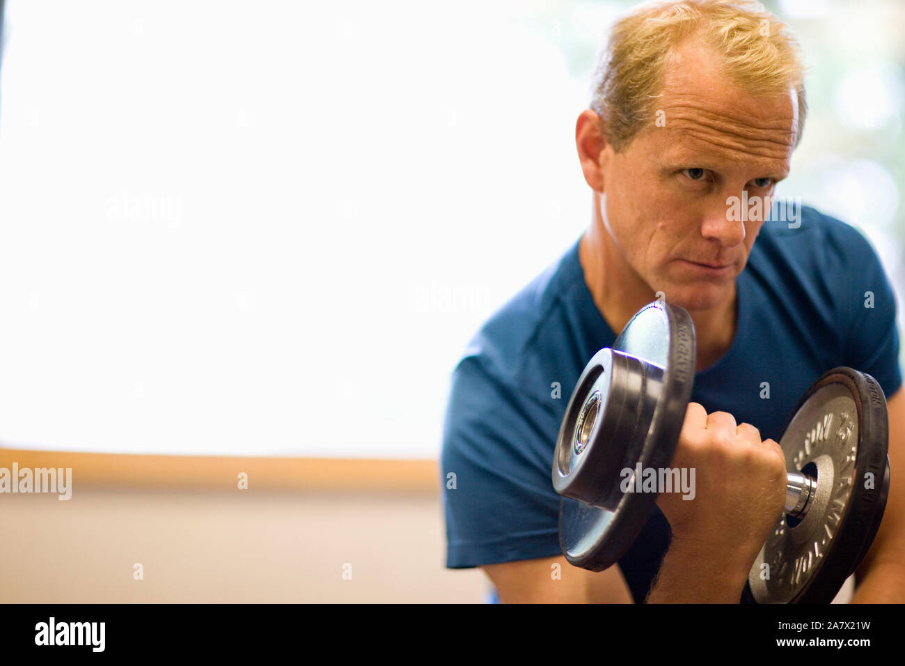 Mid-adult man lifting weights in a gym Stock Photo - Alamy