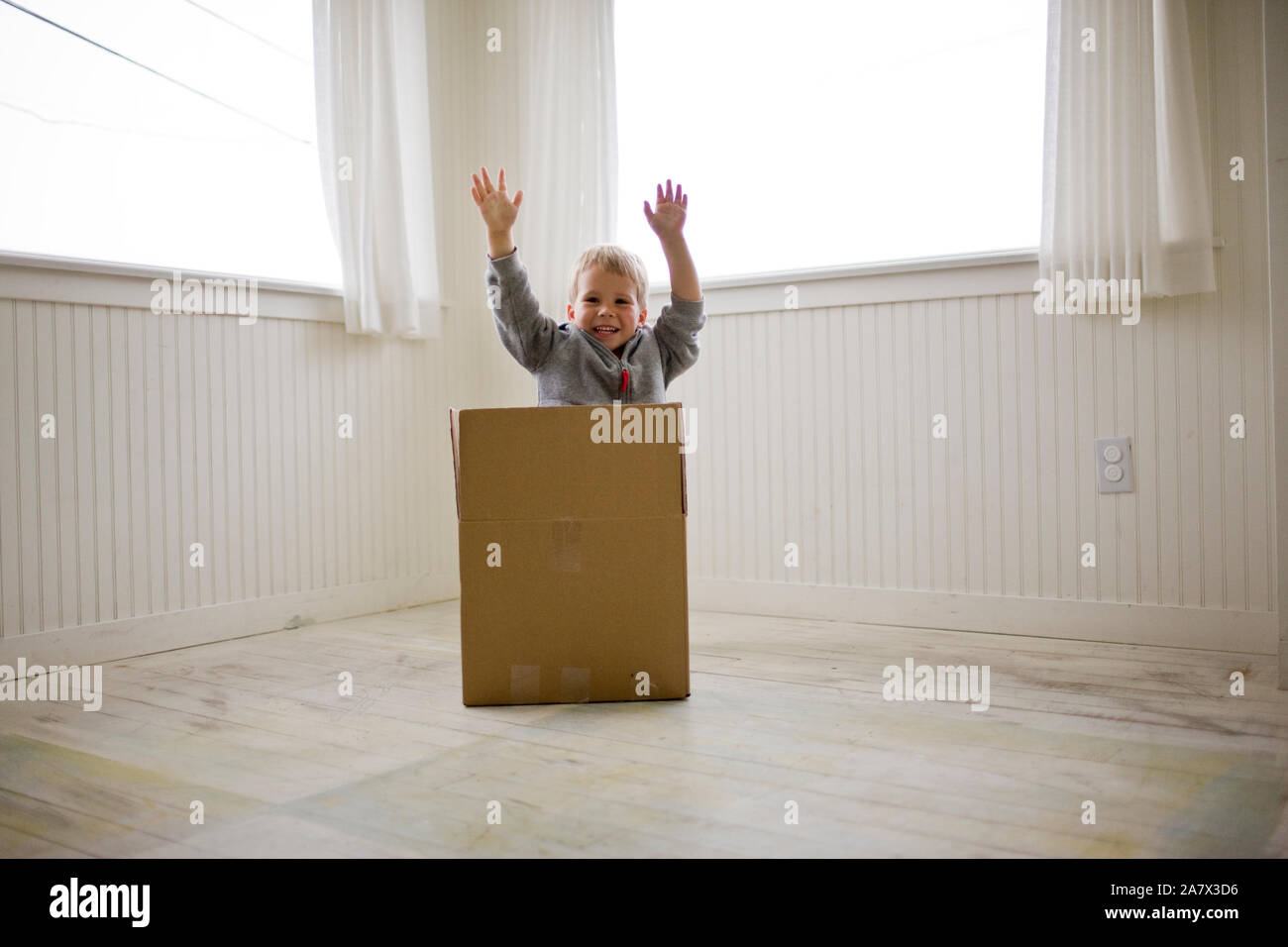 Boy jumping out of box in house Stock Photo - Alamy