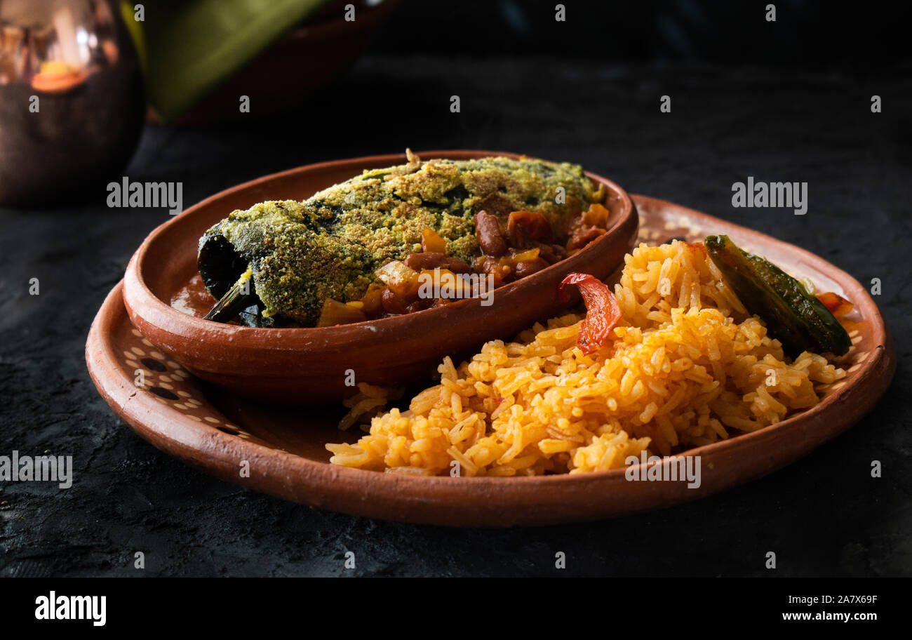Chilles rellenos and Mexican rice served in traditional clay plates ...