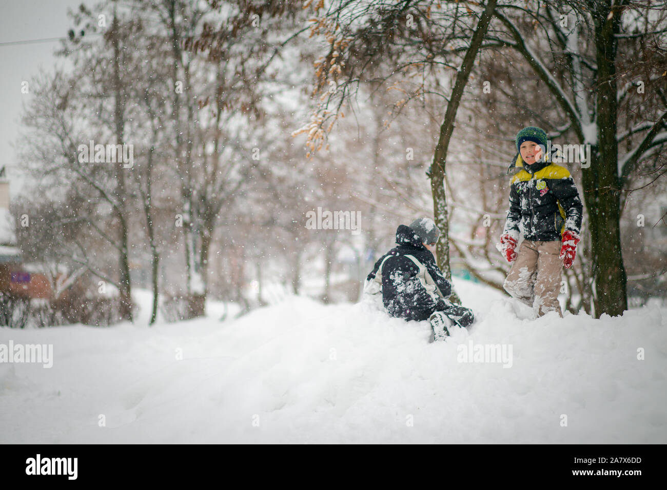 Two boys play on pile of snow after heavy snowfall in city. Children on ...