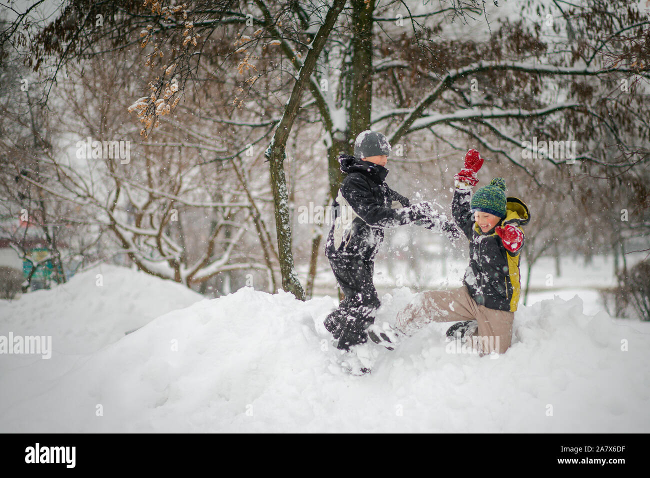 Two boys play on pile of snow after heavy snowfall in city. Children on ...