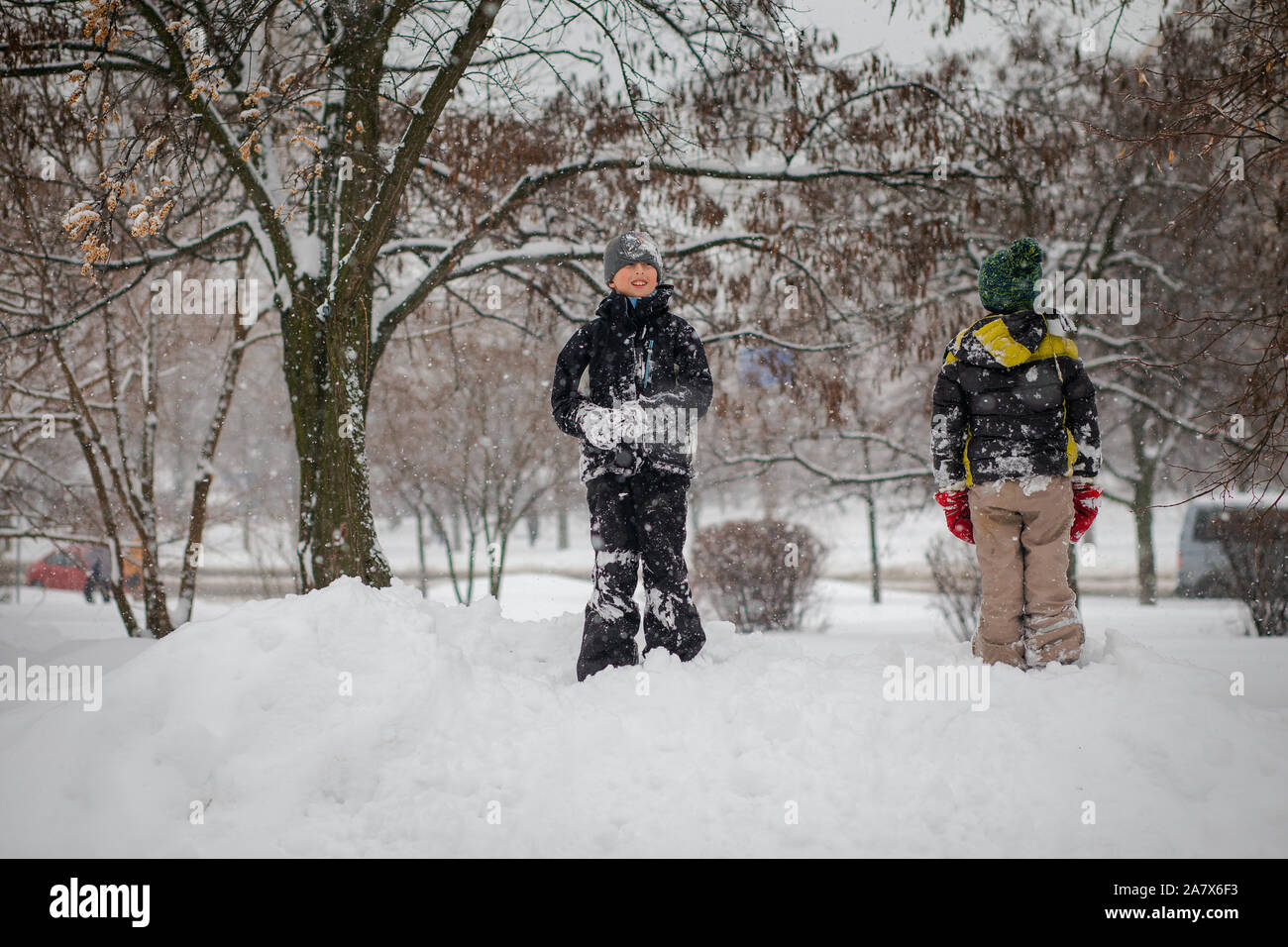 Two boys play on pile of snow after heavy snowfall in city. Children on ...