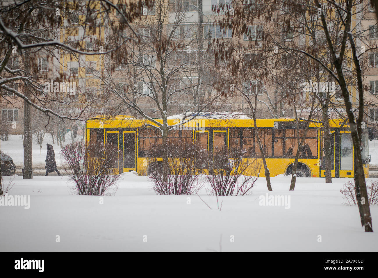 Yellow passenger bus in winter on a city street. Bus passing through ...