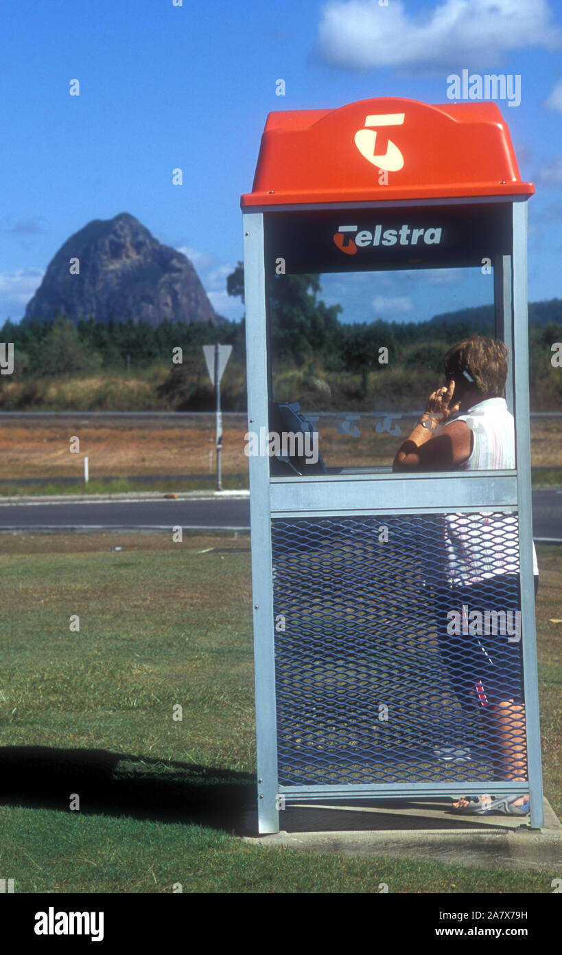 WOMAN USING TELSTRA TELEPHONE BOX, GLASSHOUSE MOUNTAINS IN THE ...