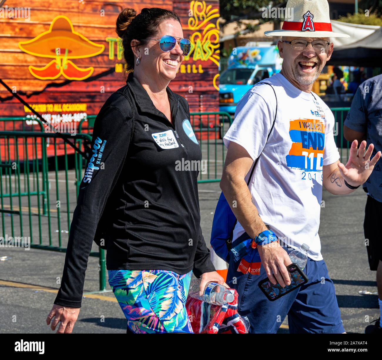 Happy couple briskly walks across the finish line. The man is laughing ...