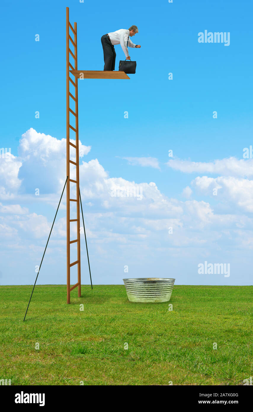 Man looking at his watch getting ready to jump off high dive into small ...