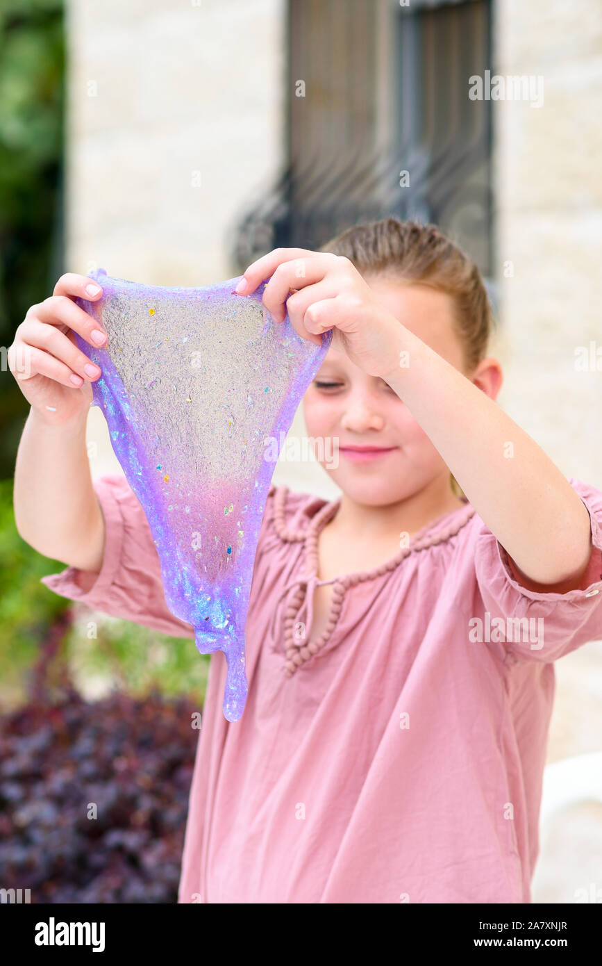 Cheerful teenager girl holding a purple slime and looking through Stock ...
