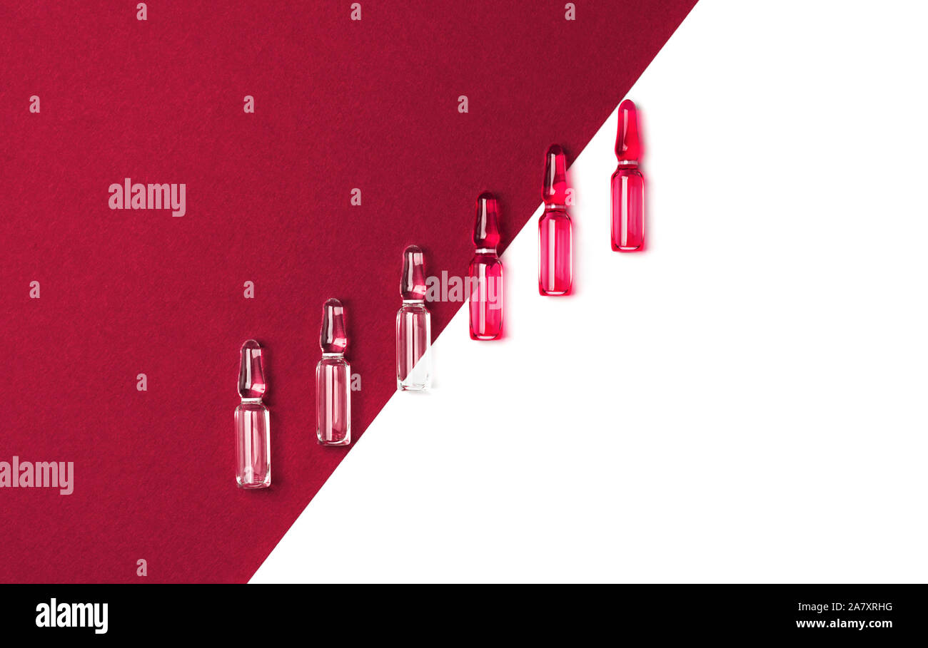 Diagonal line of ampules for injections with red and transparent liquid ...