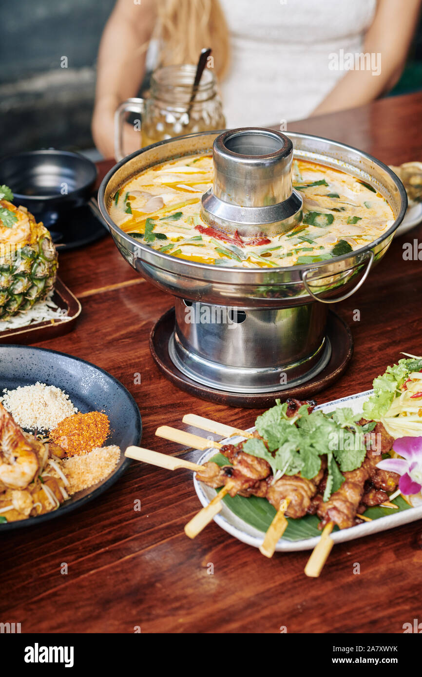 Thai spicy squid soup in metal pot and various seafood snacks on dinner ...