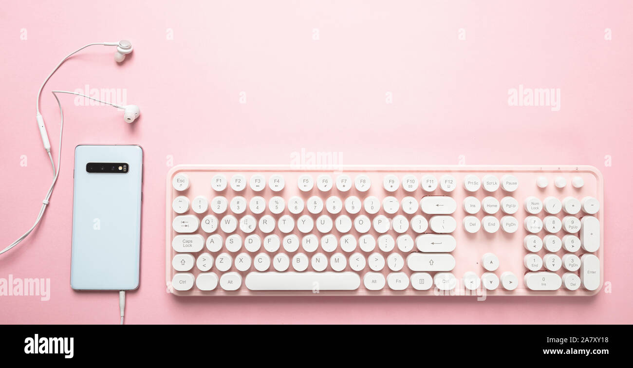 Female office desk. Mobile phone back view white color with earphones ...