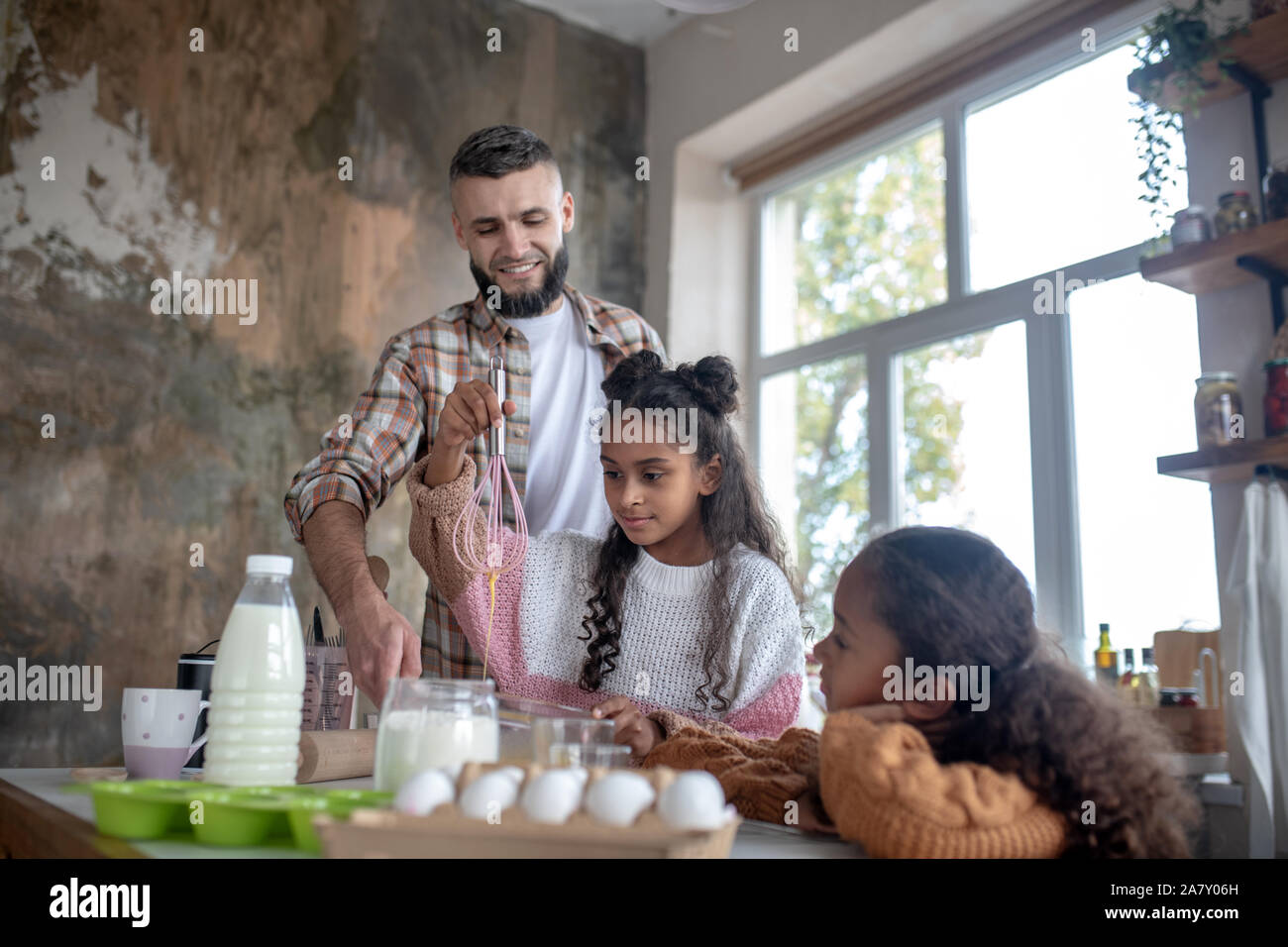 Two girls feeling curious while cooking pie with father Stock Photo - Alamy
