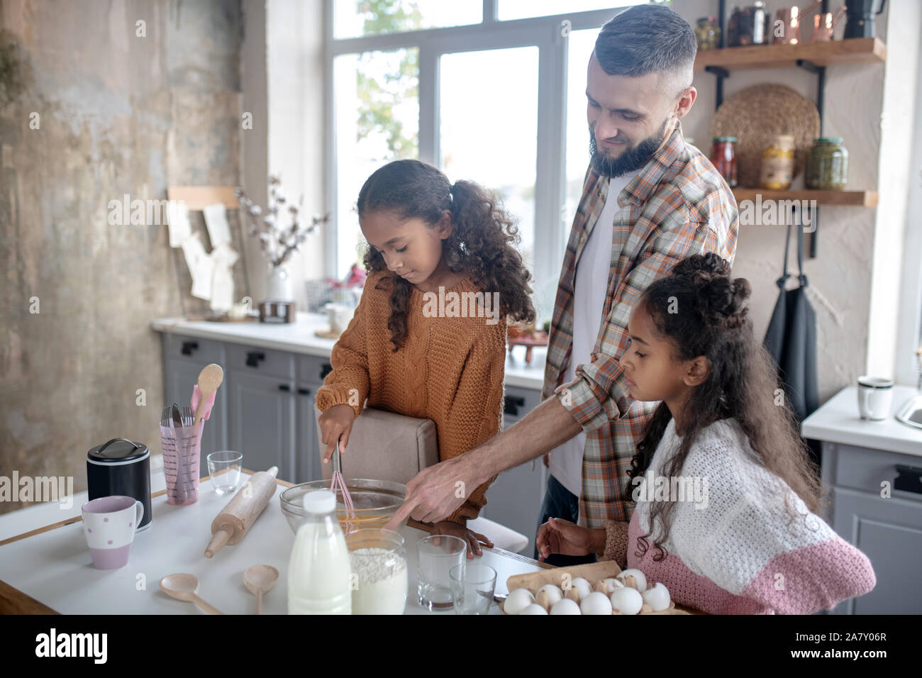 Daughter trying to whip eggs while cooking with daddy Stock Photo - Alamy