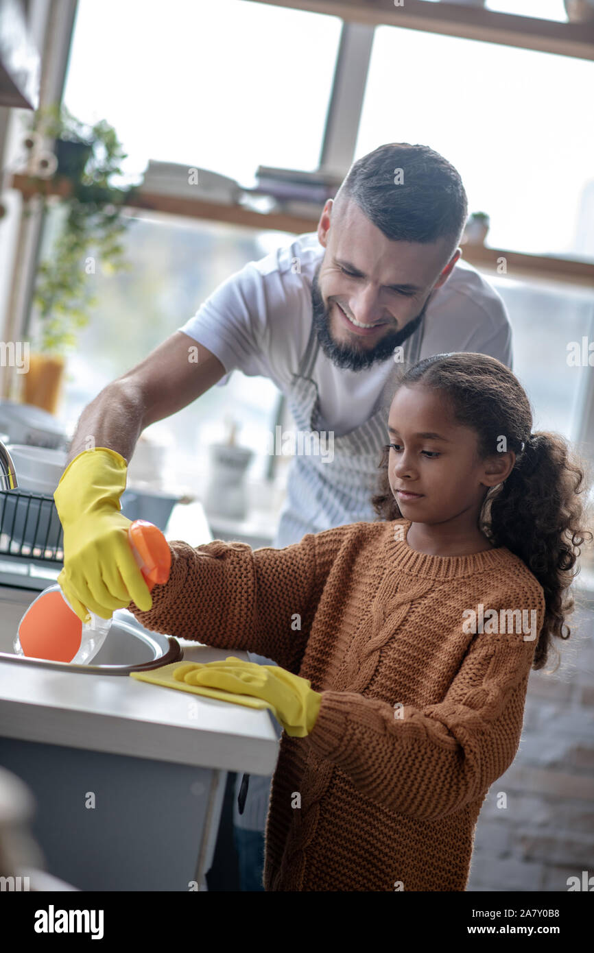 Daddy smiling while cute daughter cleaning kitchen Stock Photo - Alamy
