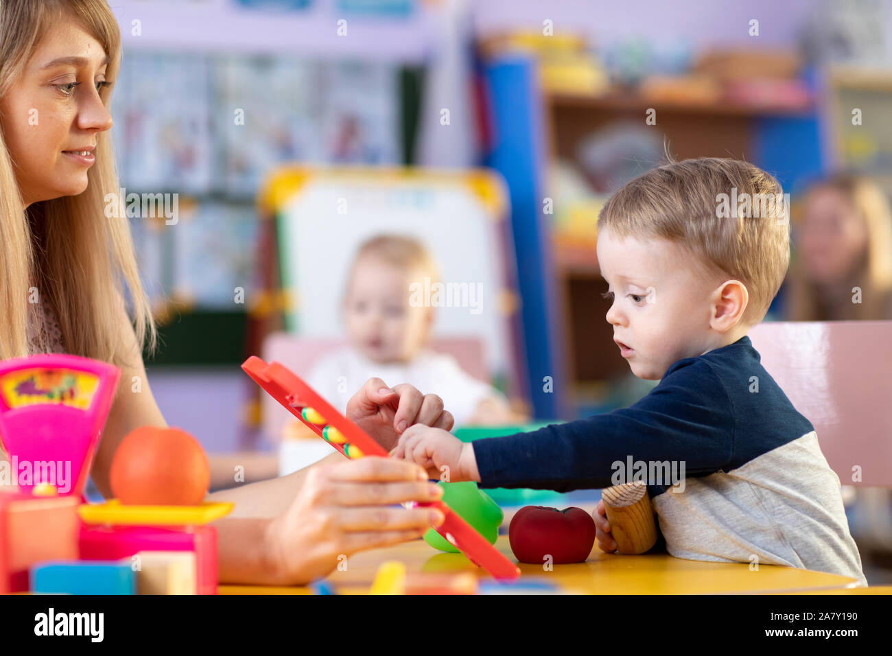 Kids with preschool teacher play role game in toy shop at nursery or ...