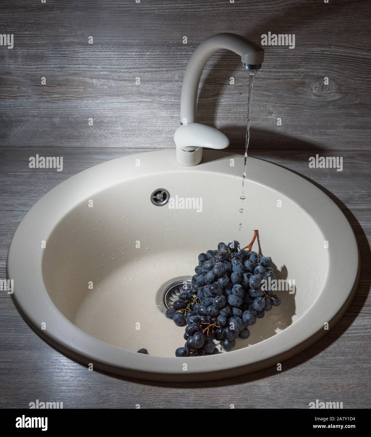 Washing a branch of grapes in the sink Stock Photo - Alamy
