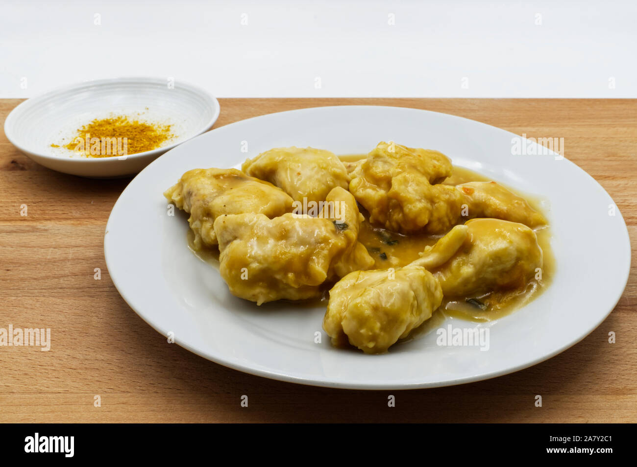 Chicken curry served in a white dish, wooden table, white background ...