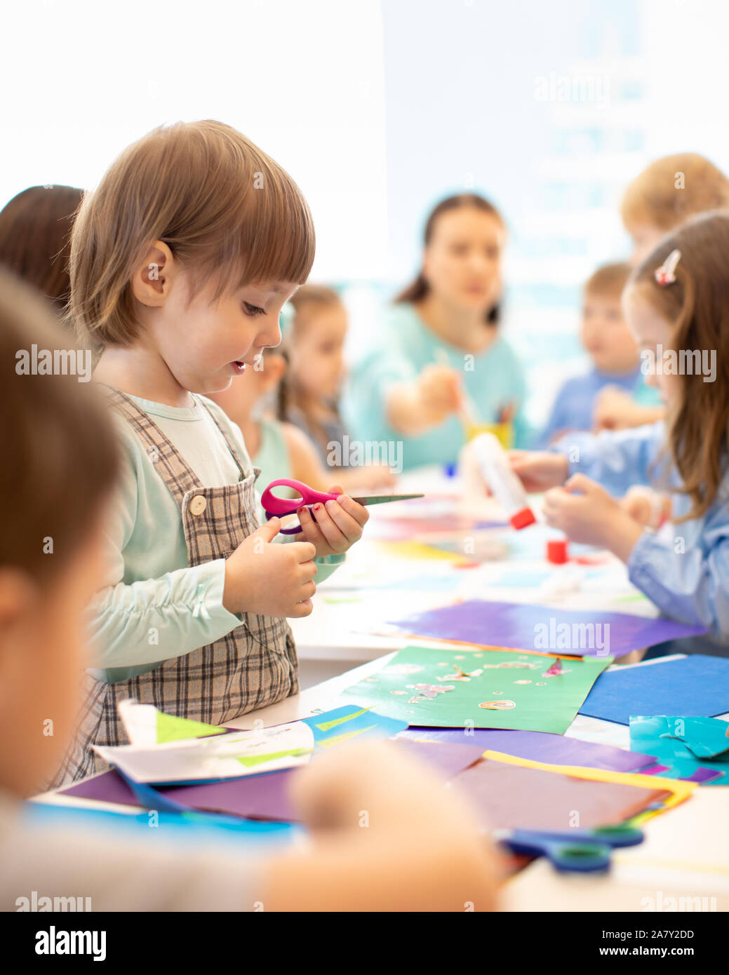 Group of preschool children cutting scissors out paper in kindergarten ...