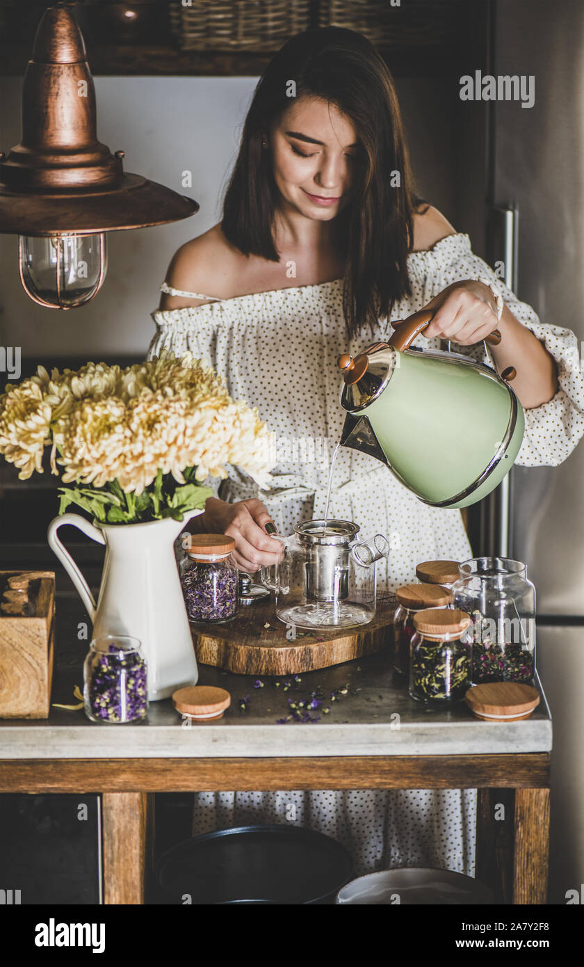 Young woman brewing tea in glass pot at kithcen counter Stock Photo - Alamy