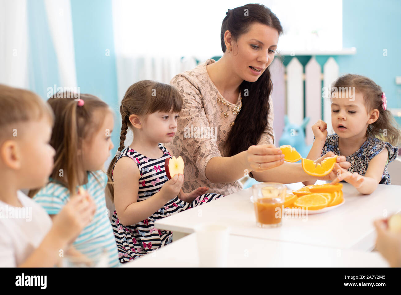 kindergarten teacher and preschoolers having break for fruits and ...