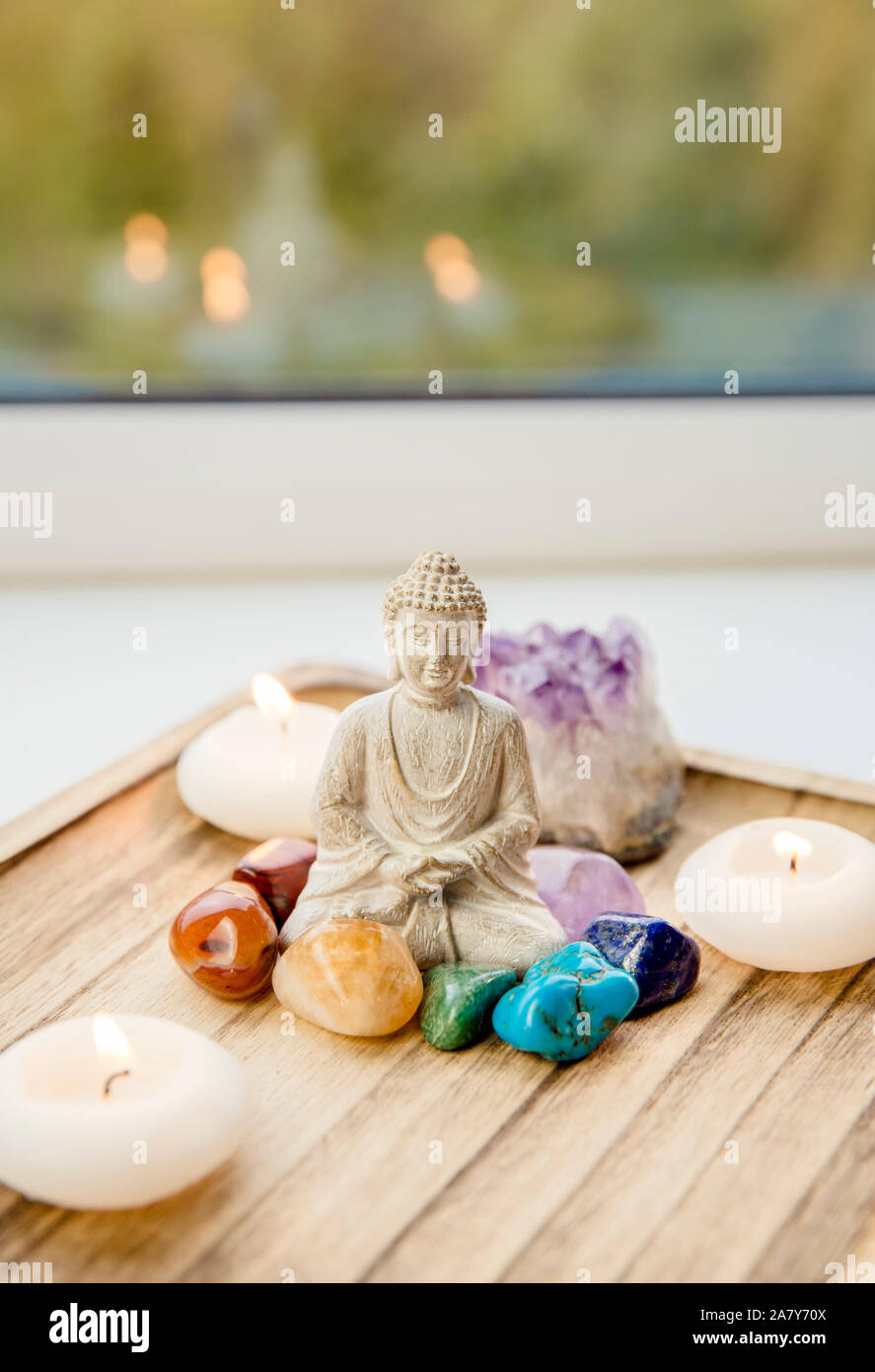 All seven chakra colors crystals stones around sitting Buddha figurine ...