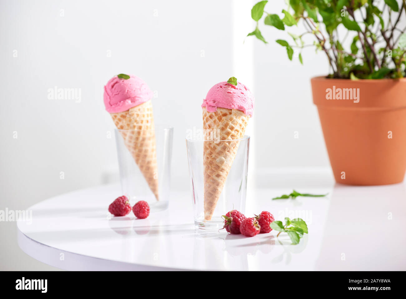 Waffle cone filled with fresh raspberry ice cream in glass cup with ...