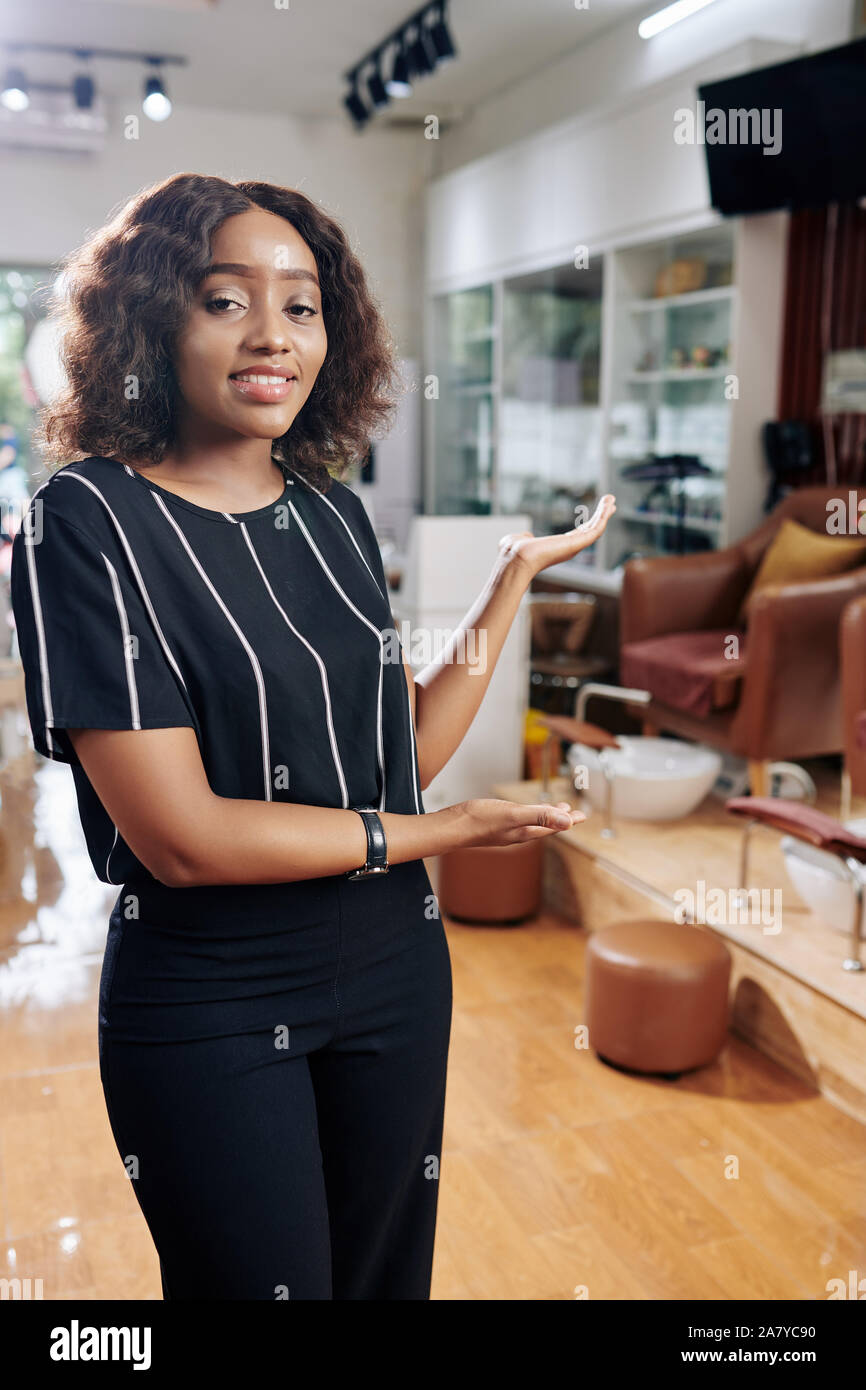 Portrait of young smiling pretty woman welcoming customers in her ...